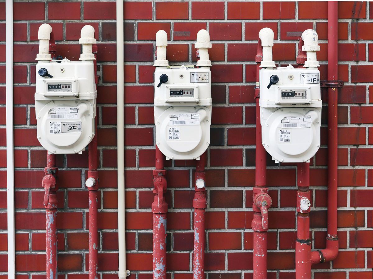 Three gas meters on dark red brick walls | GANREF